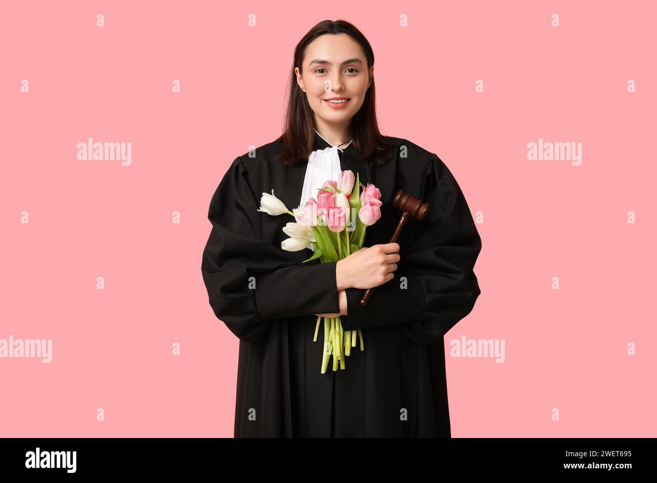 Portrait of young female judge with bouquet of flowers on pink ...