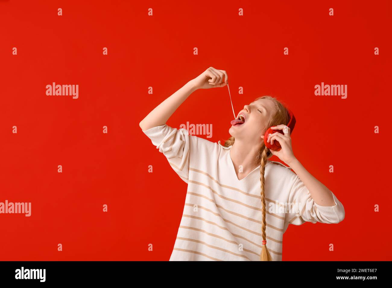 Teenage girl in headphones chewing gum on red background Stock Photo ...
