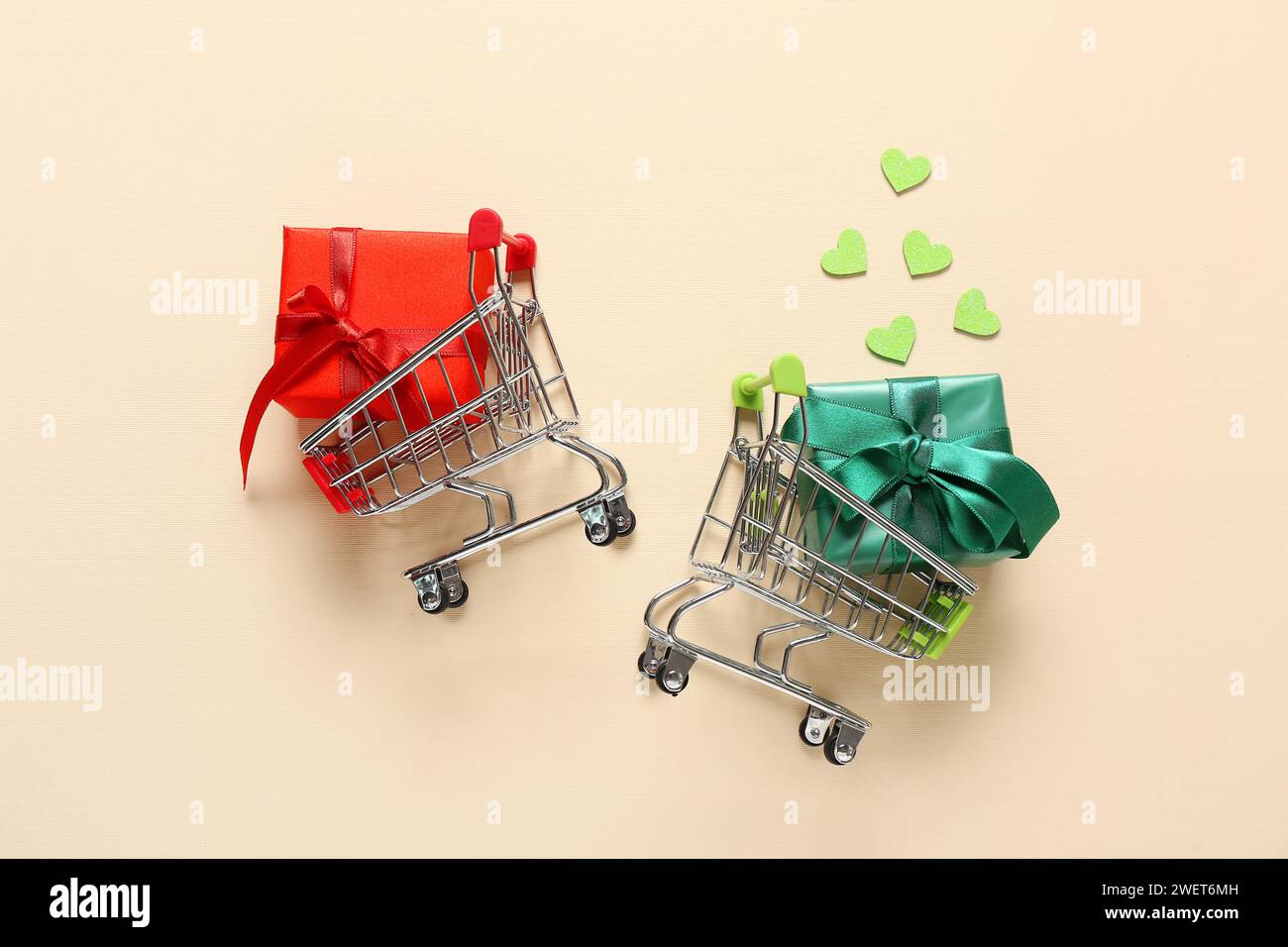 Small shopping carts with gift boxes and paper hearts on beige ...
