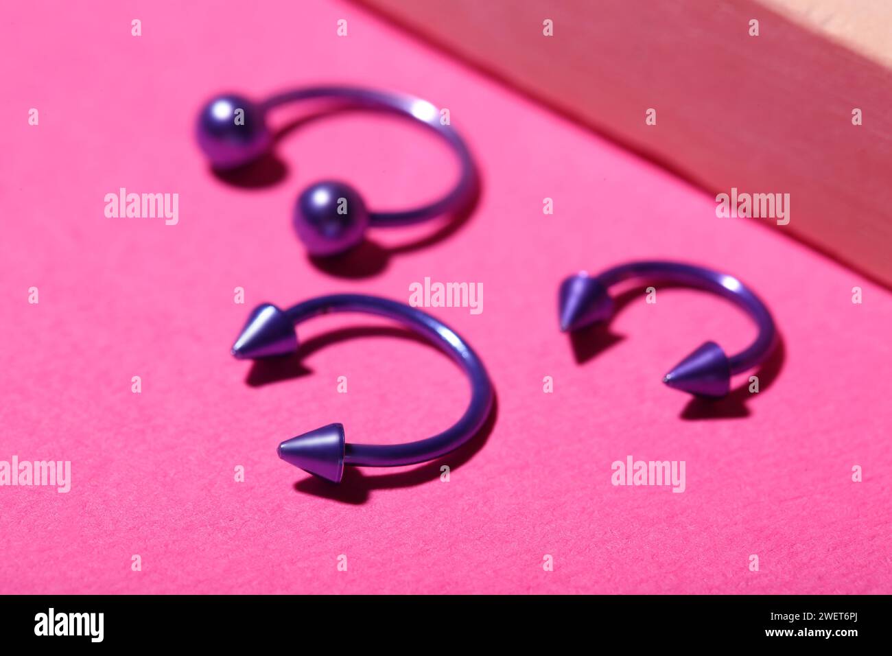 Circular barbells for piercing on pink background Stock Photo - Alamy