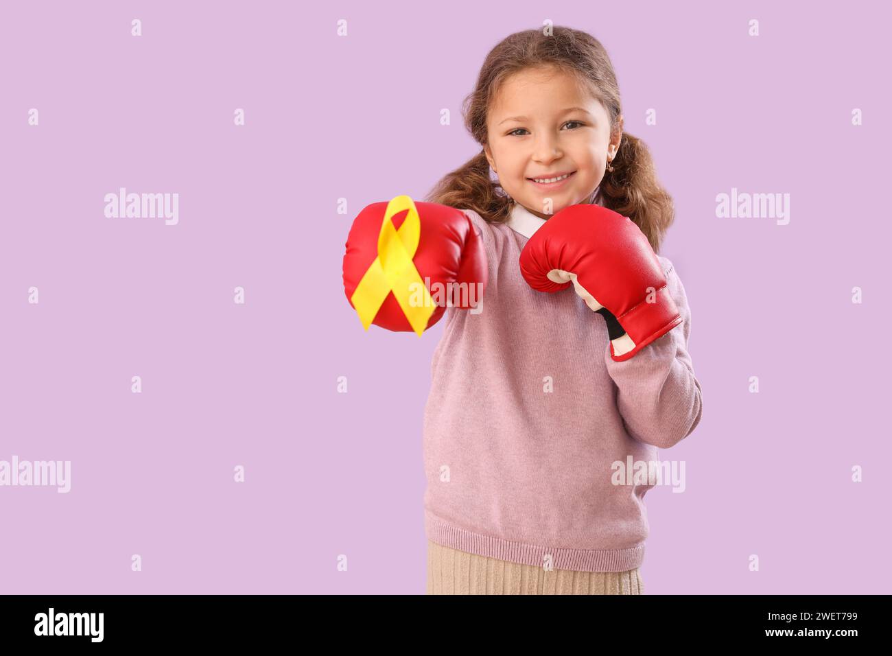 Cute little girl in boxing gloves with yellow ribbon on lilac ...