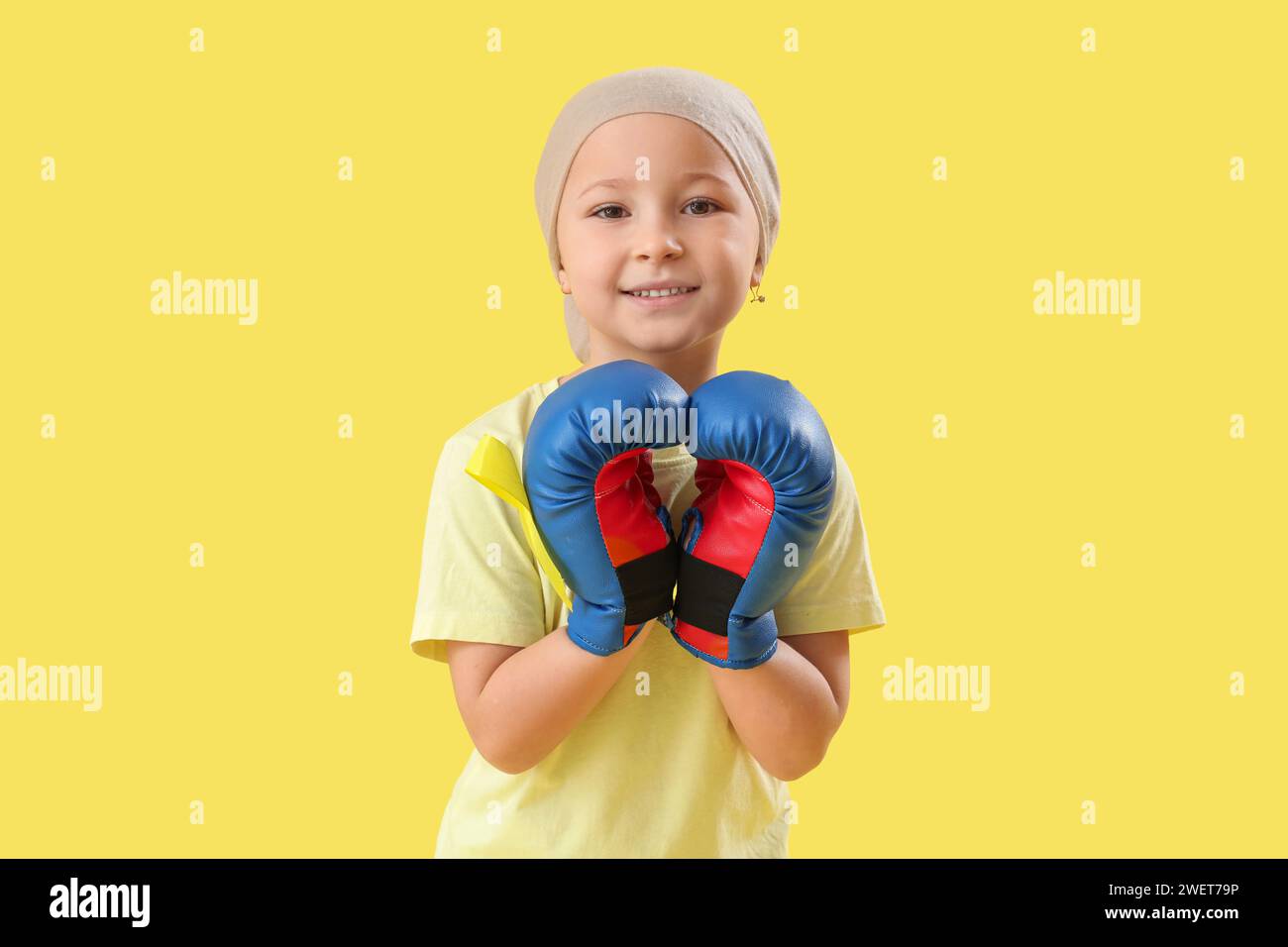 Cute little girl in boxing gloves with yellow ribbon on color ...