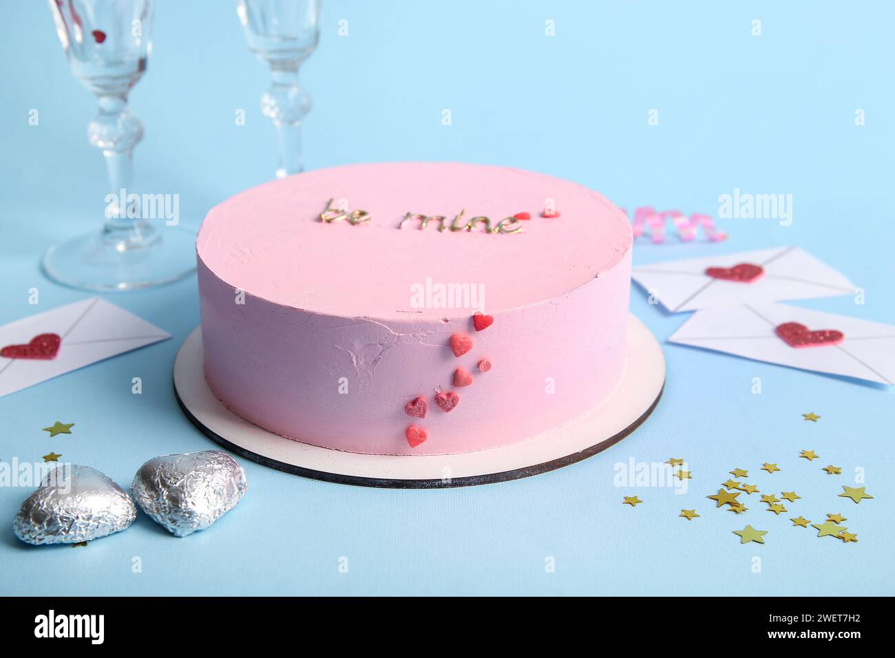 Pink bento cake with envelopes and candies on blue background ...