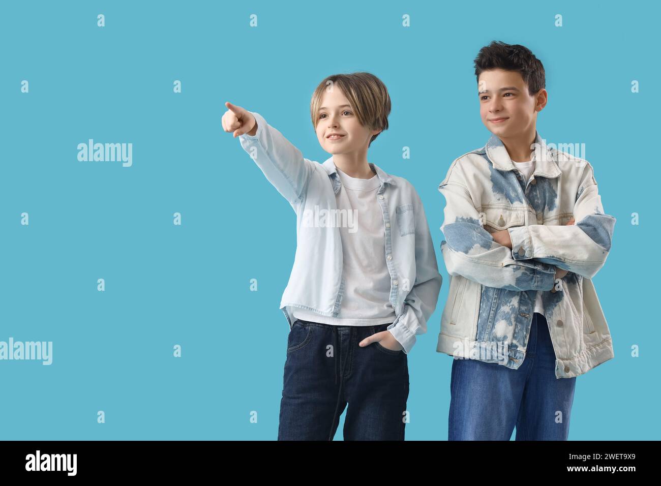 Happy brothers pointing at something on blue background Stock Photo - Alamy