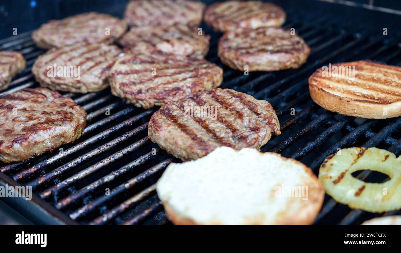 Grilled hamburger meat and buns with pineapple on stainless BBQ grill ...