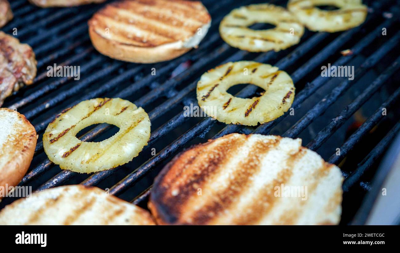 Grilled hamburger buns with pineapple on stainless BBQ grill with ...
