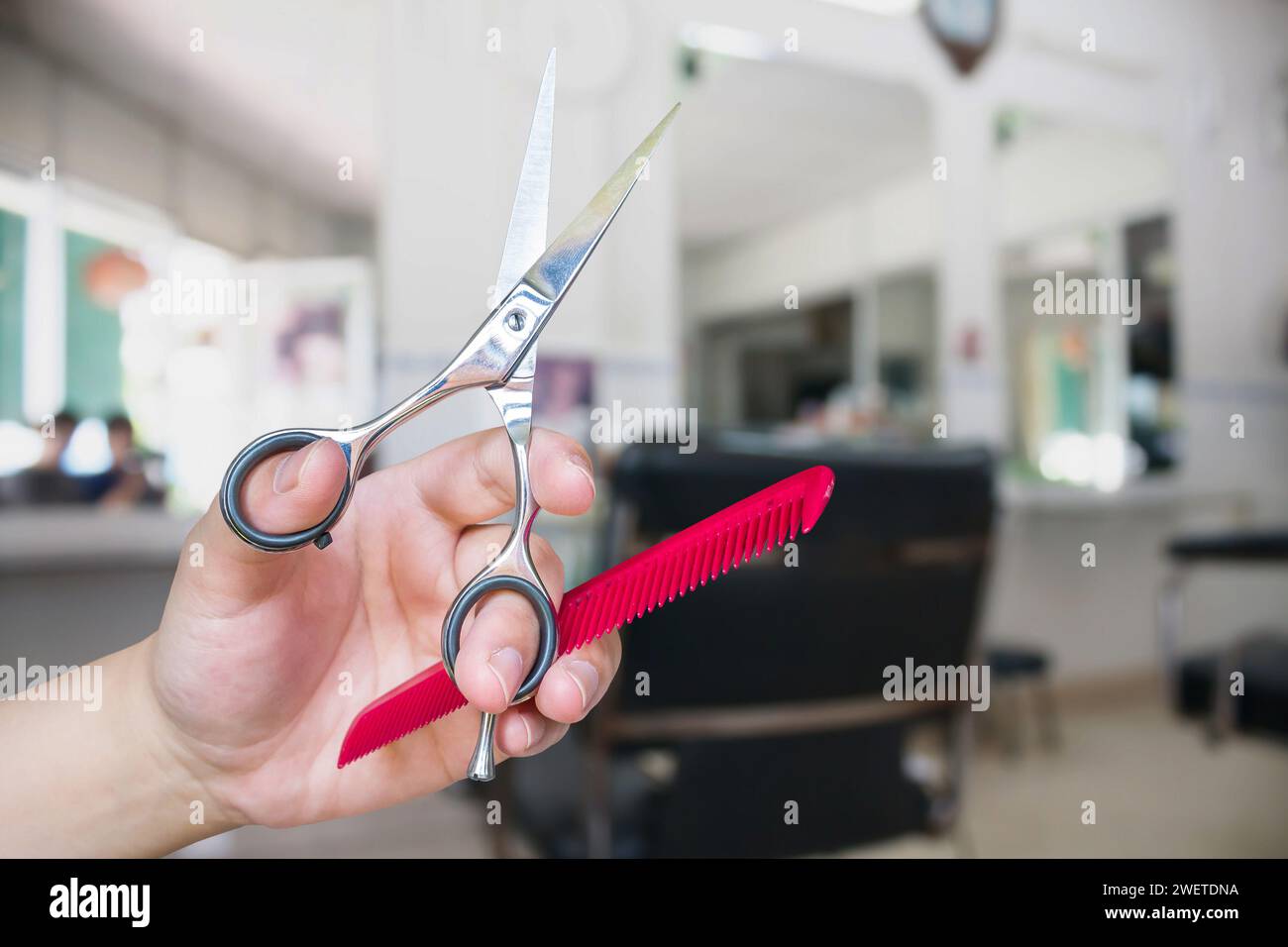 Hairdresser's hand hold scissors with salon beauty interior blur ...