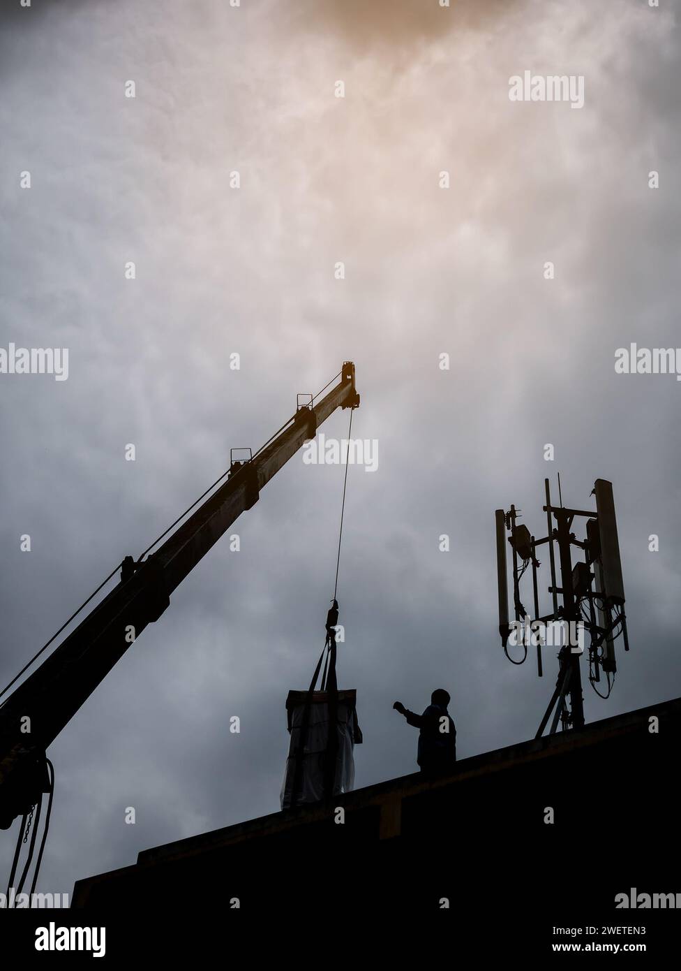 Industrial Crane operating and lifting electric box against clouds and ...