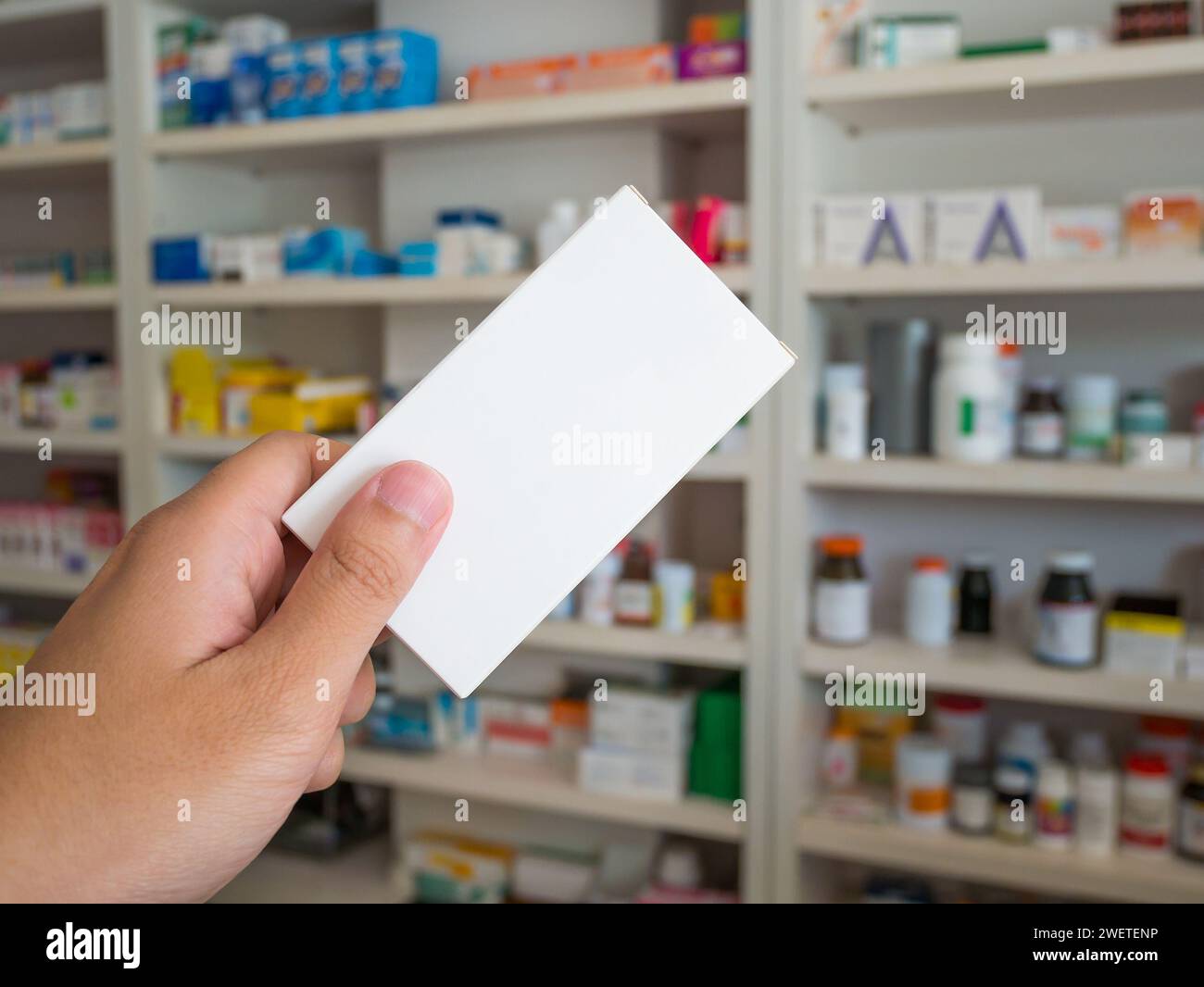 Close up pharmacist hand hold medicine box package with shelves of ...