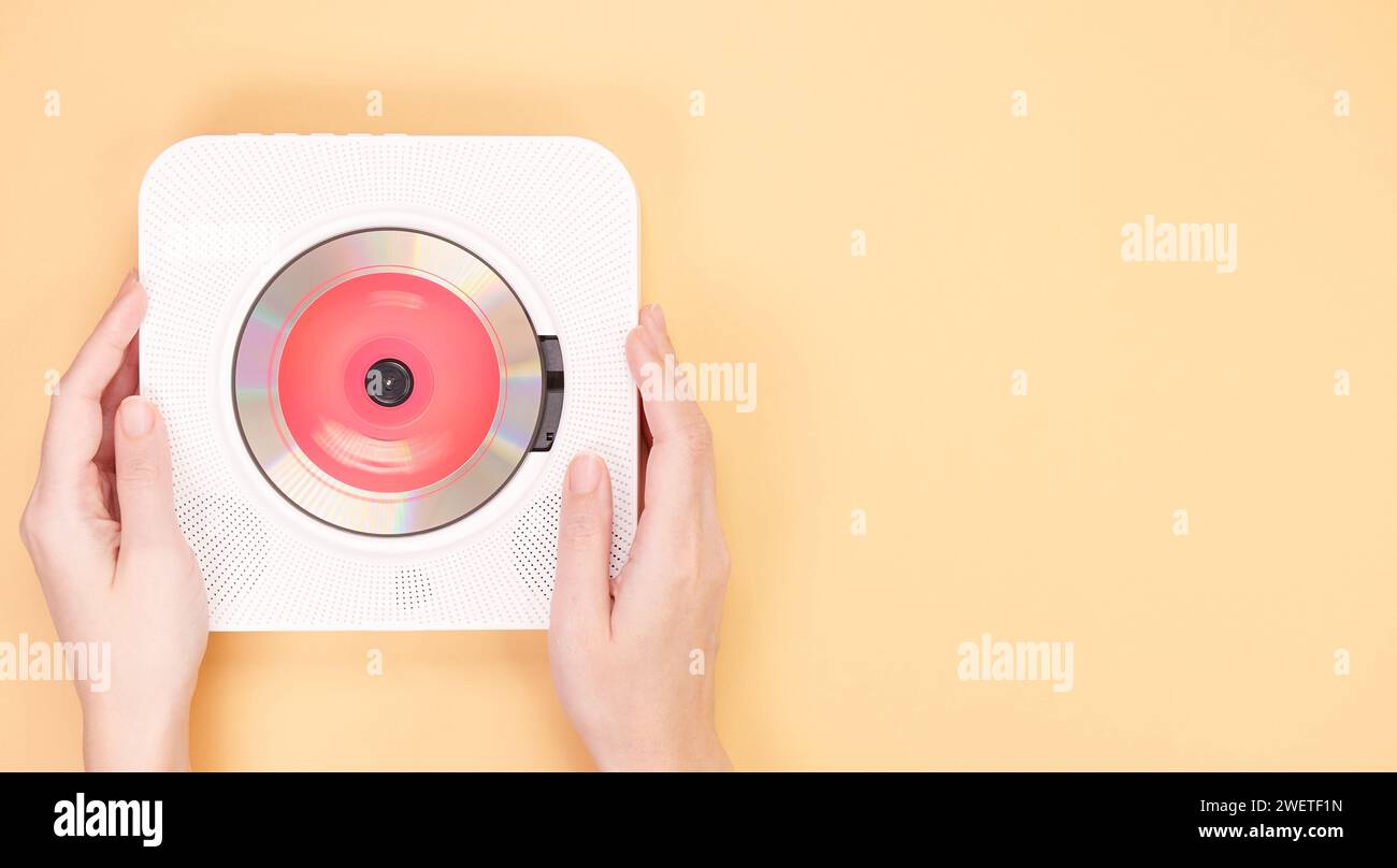 Hands holding stylish white portable compact CD player with red cd disc ...