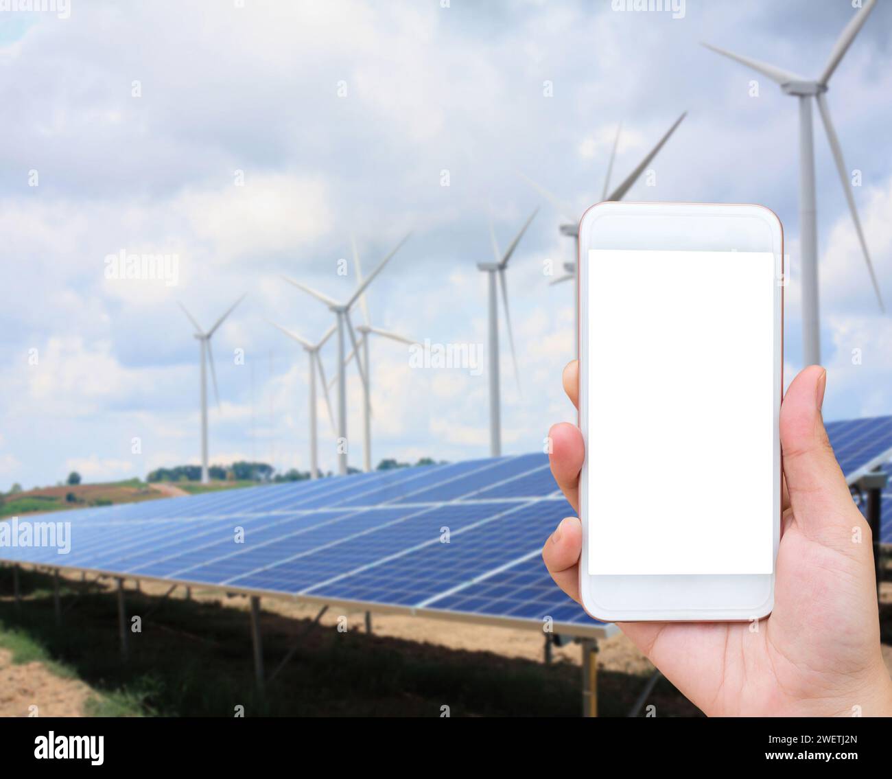 hand holding mobile phone with solar panels and wind turbines ...