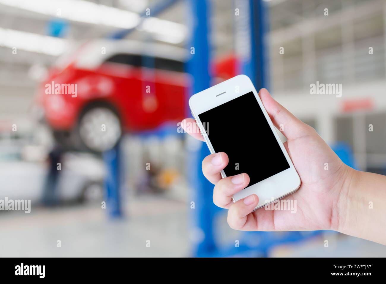 woman hand hold touch screen mobile smart phone with car garage ...