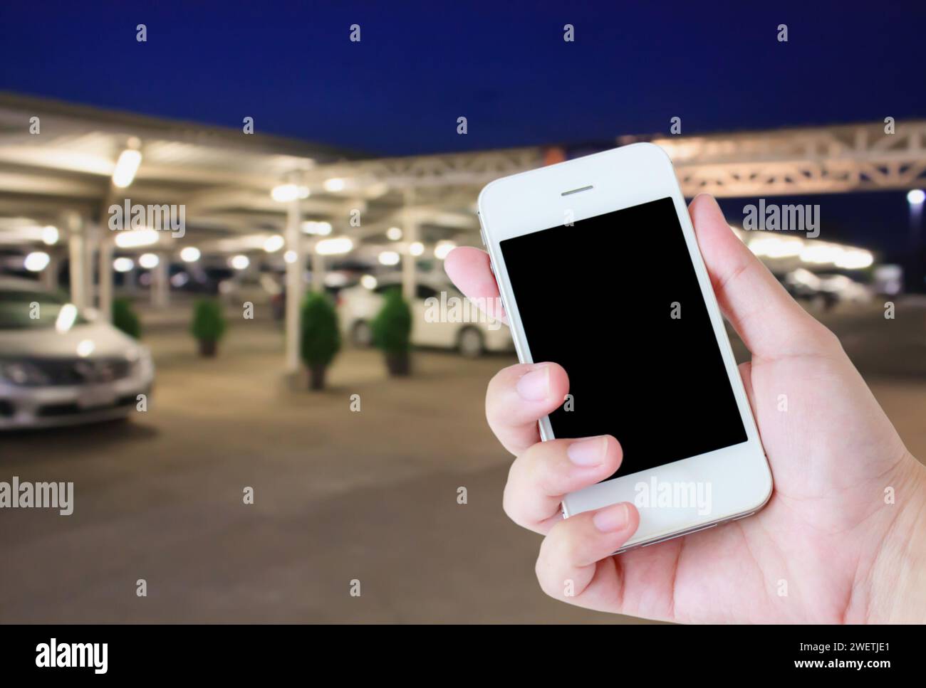 Mobile hold in hand with blur cars parking Stock Photo - Alamy