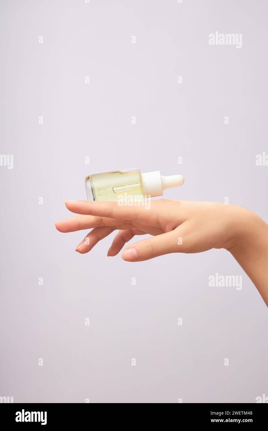 Front view of an unlabeled glass bottle containing light yellow essence ...