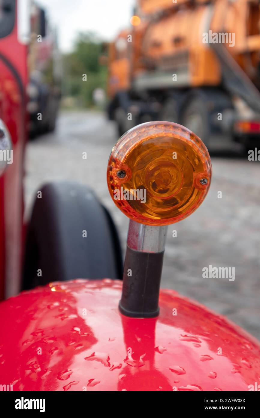 An orange car lamp on a red car wing on the background of a heavy ...