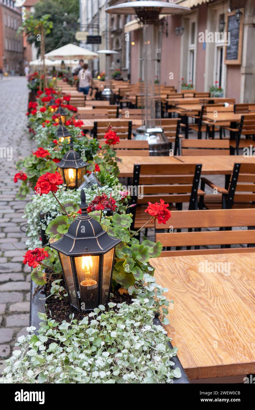 Red flowers in an outdoor terrace cafe with a lighting lamp between ...