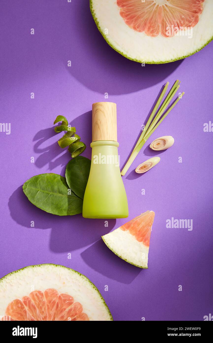 Top view of empty glass bottle, fresh pink pomelo slices, green leaves ...