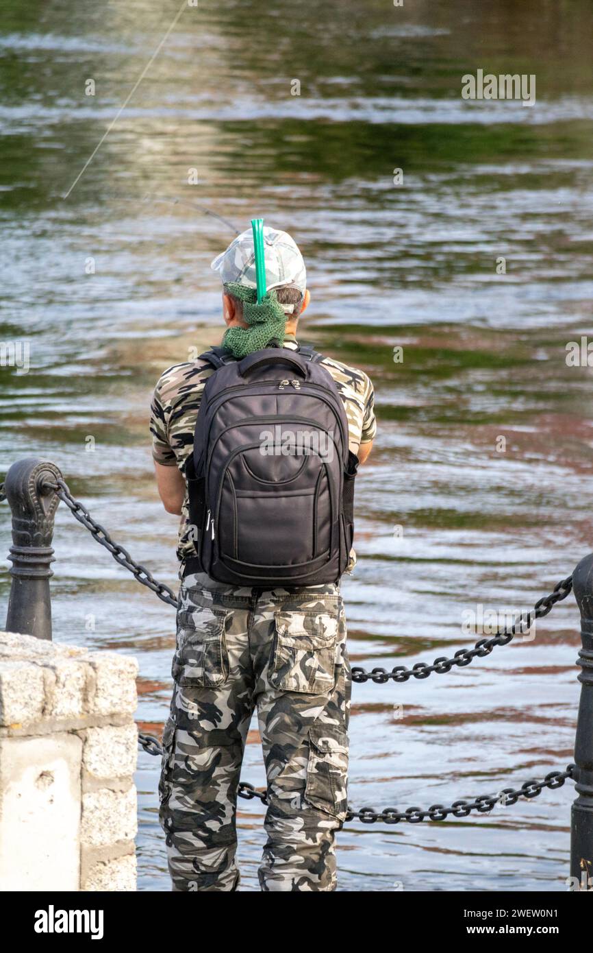 A fisherman in the color of an army uniform with a backpack on his back ...