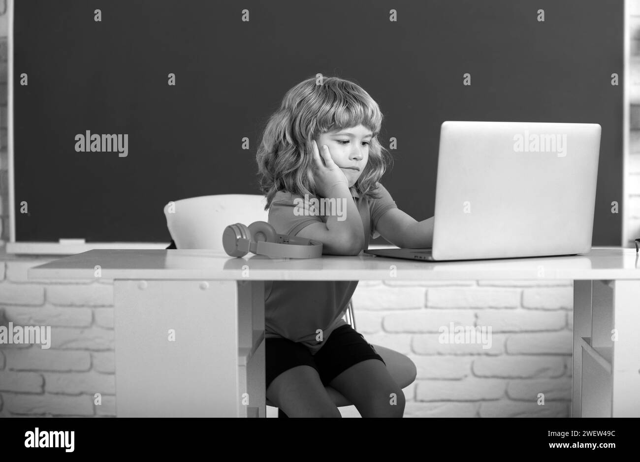 Kid boy learning lesson at school, making homework and using notebook ...