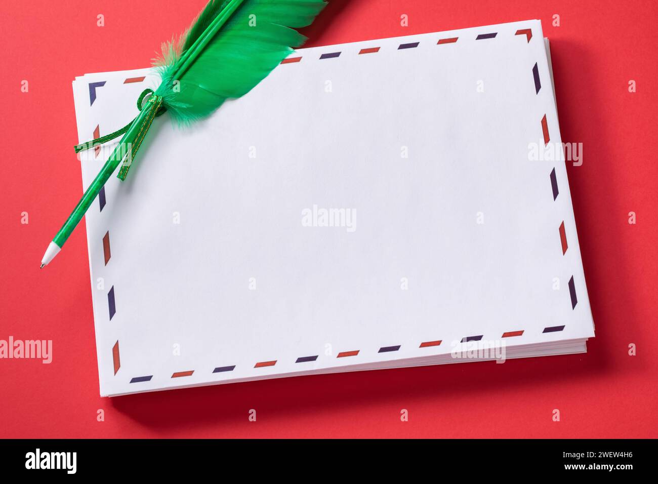 Stack of white greeting envelopes with a pen-shaped feather on a red ...