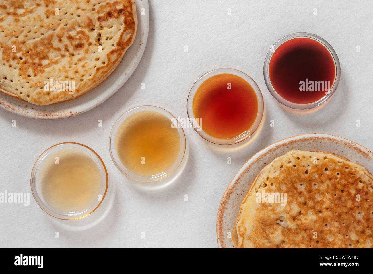 Different classes of maple syrups in different colours in glass bowls ...