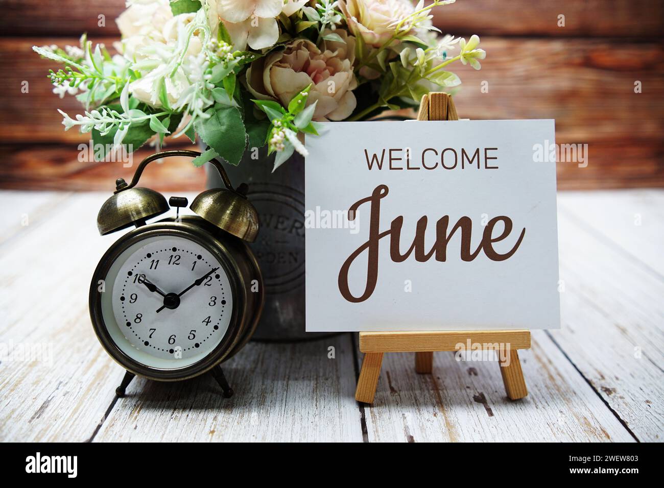 Welcome June text message written on paper card with wooden easel and ...