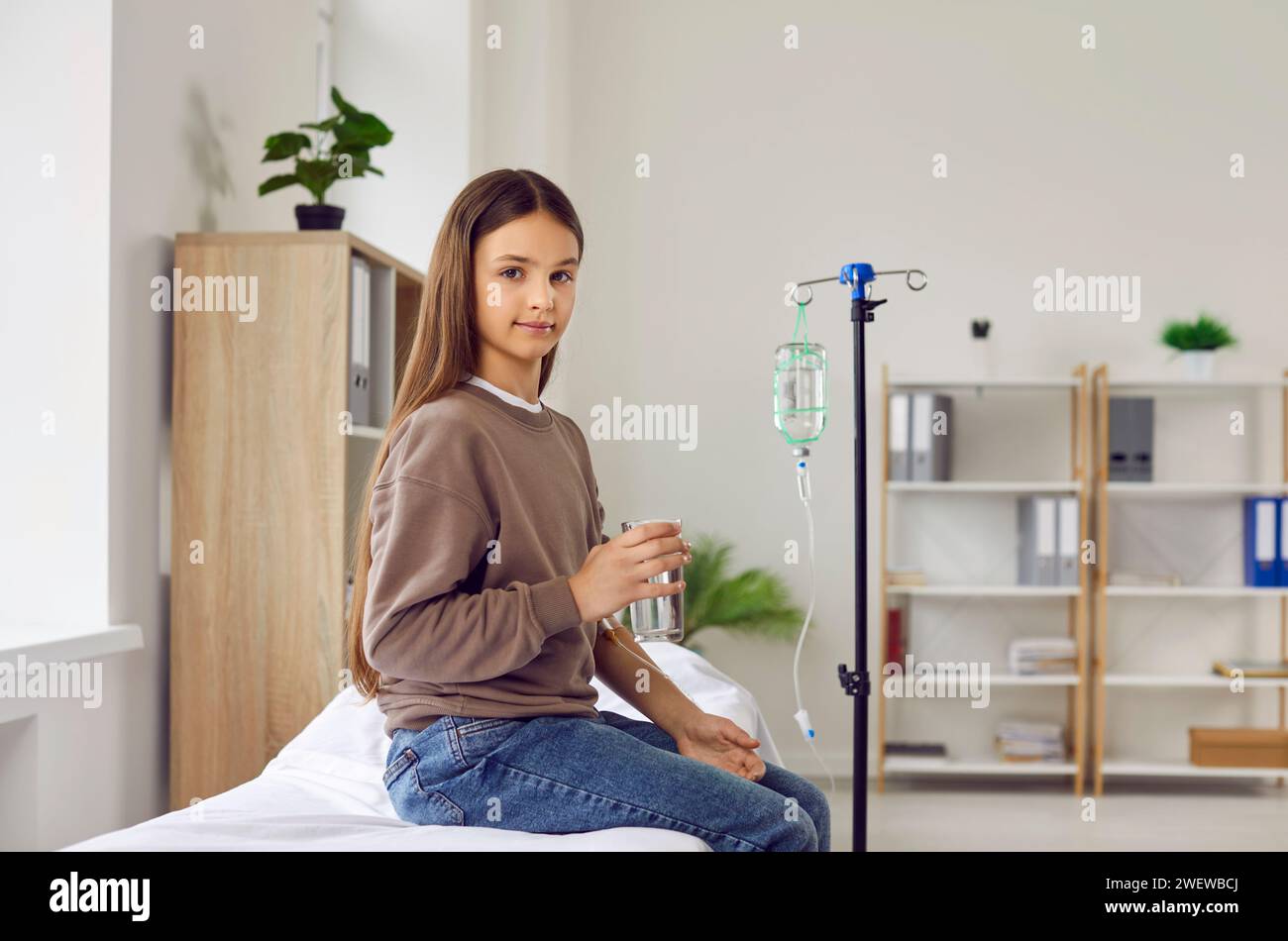Portrait of cute teenage girl patient in hospital with IV saline drip ...