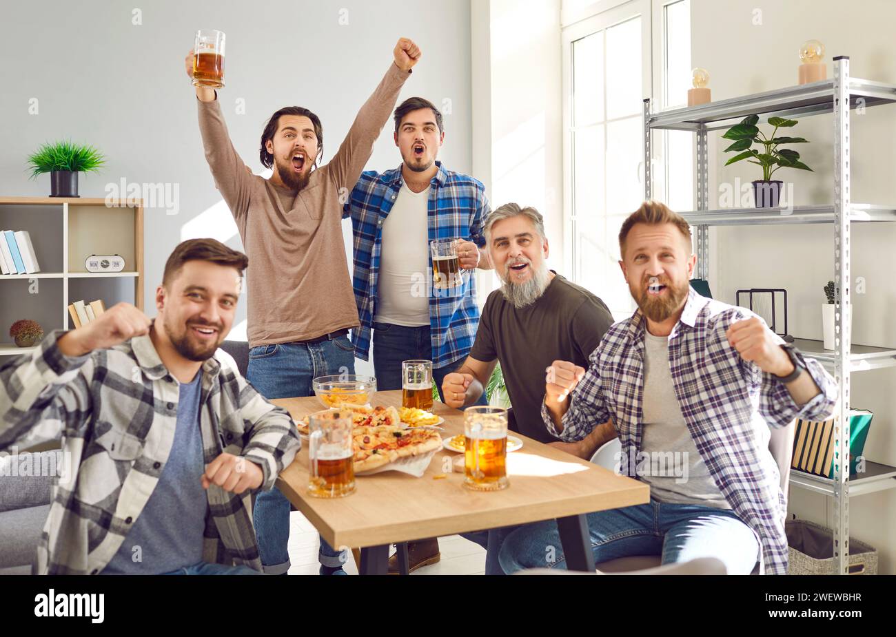Group of male friends enjoying weekend, having party, watching football ...