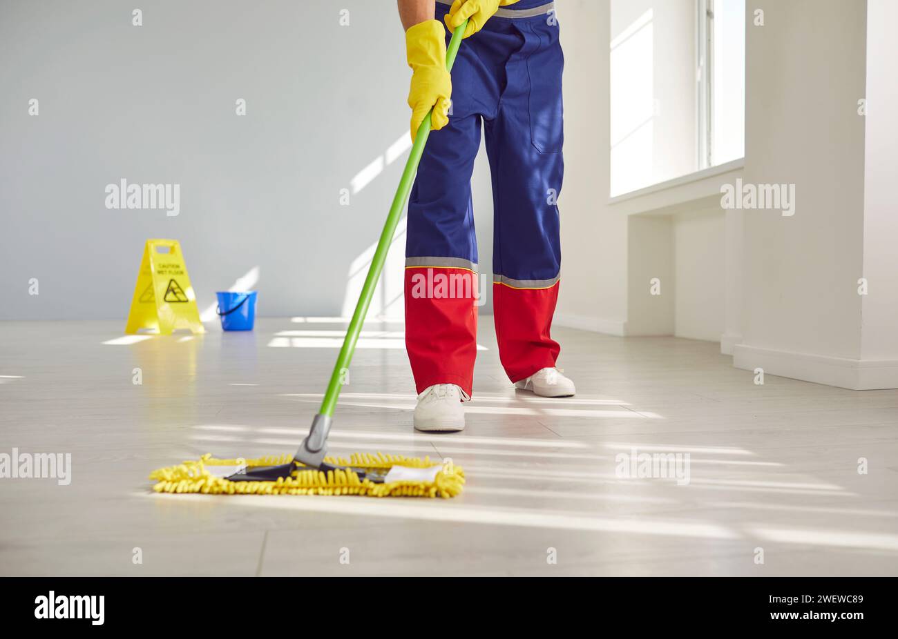 Low angle cropped photo of male janitor legs cleaning floor with mop ...