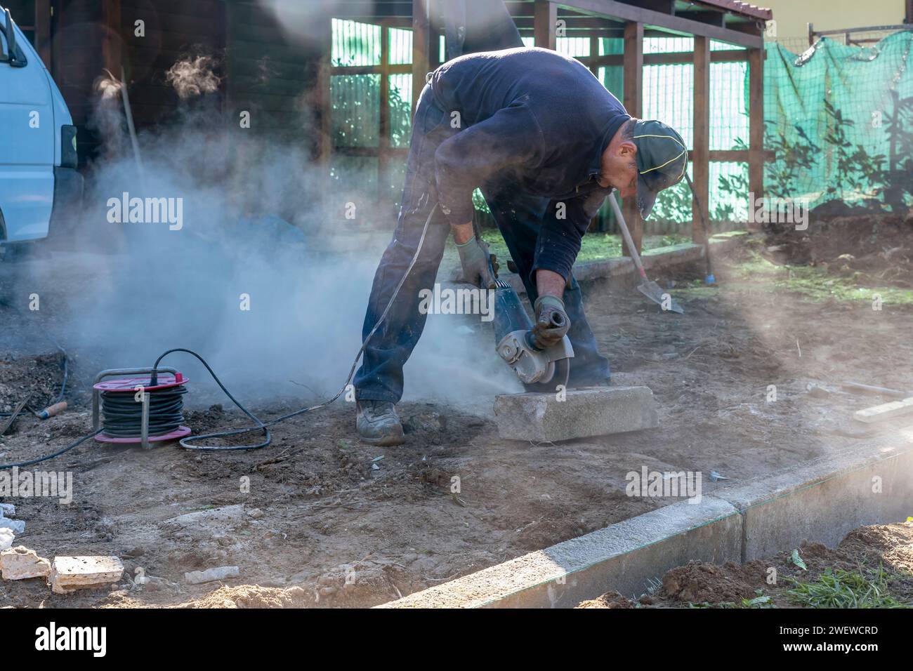 A construction worker cuts a concrete curb using a professional angle ...