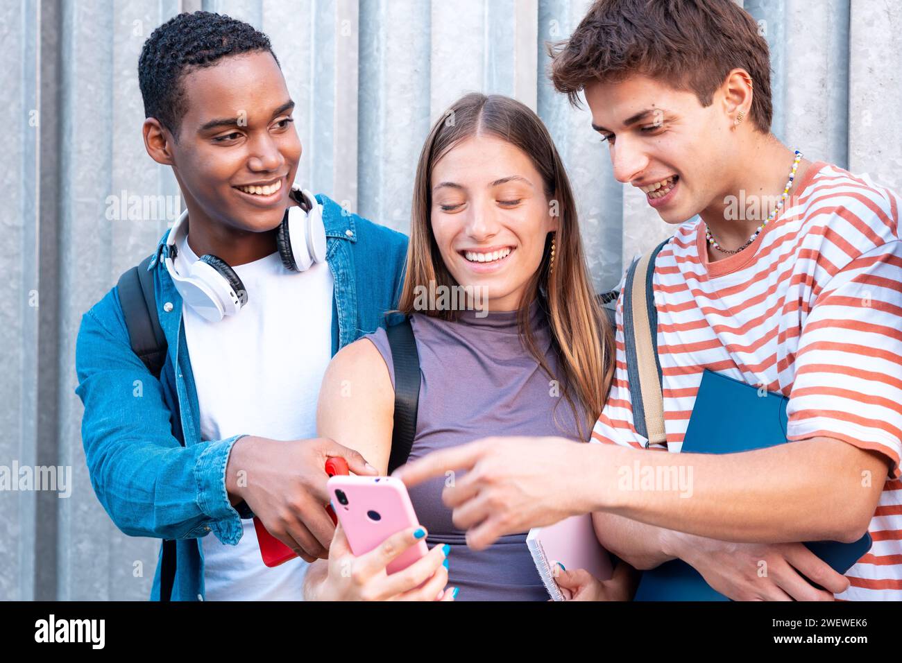 three college students laughing, looking at social media on smartphone ...