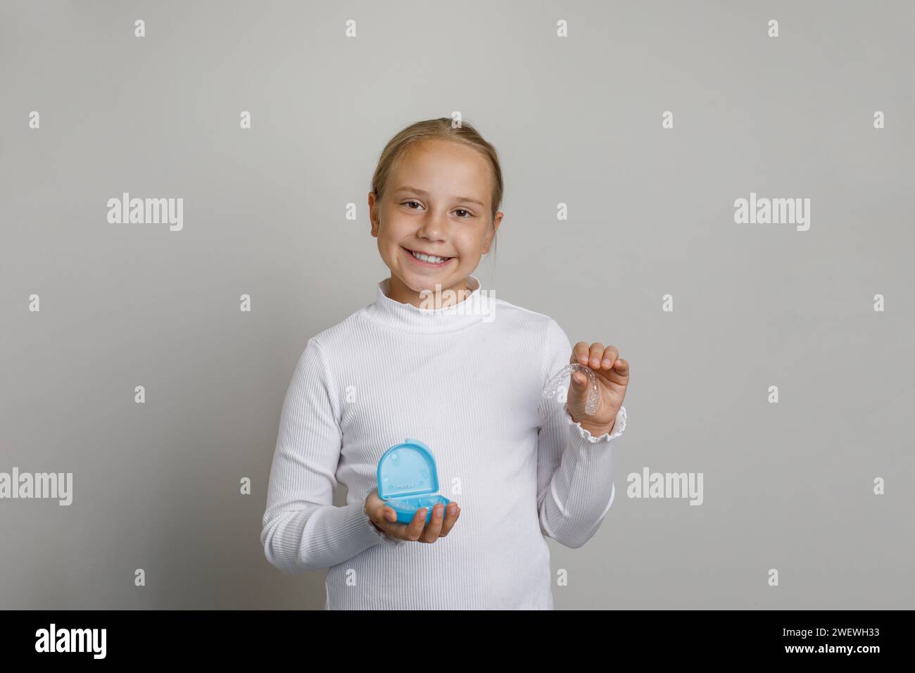 Cute young child girl holding invisible aligners for whitening and ...