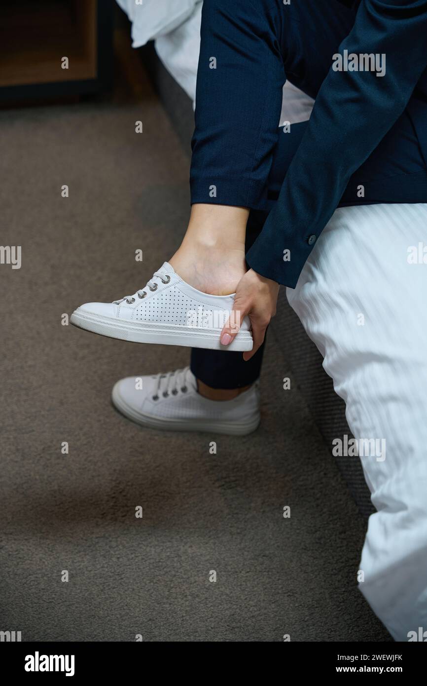 Female person is taking off pair of trendy trainers in bedroom Stock ...
