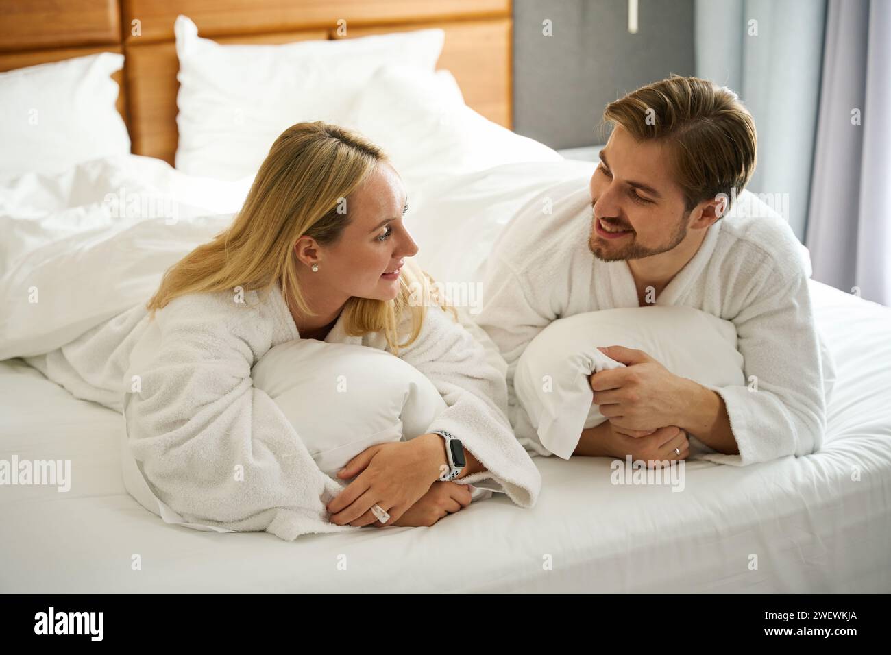 Guy and his girlfriend are talking while lying on large bed Stock Photo ...