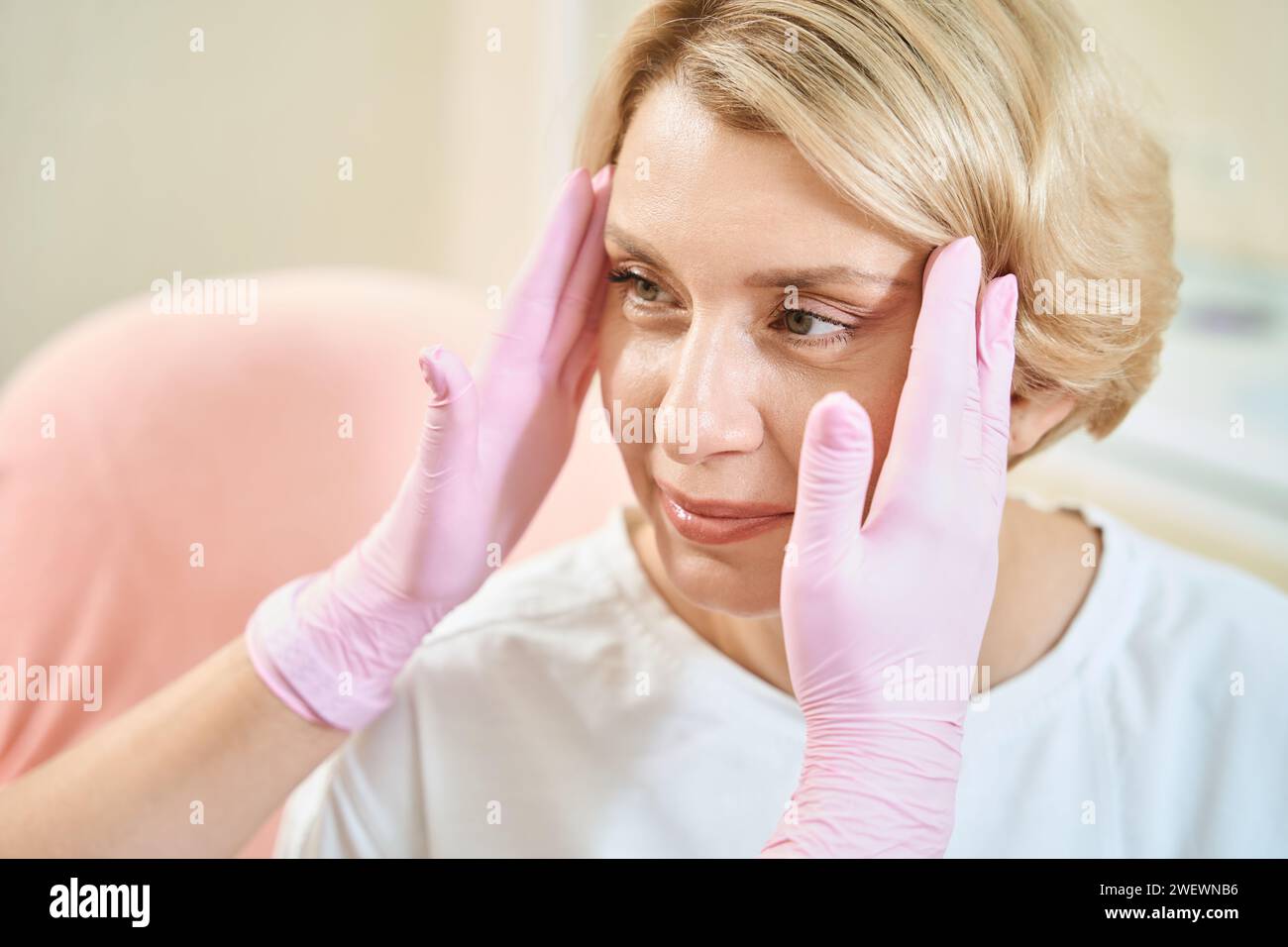Partial female beautician examining and touching face of adult ...