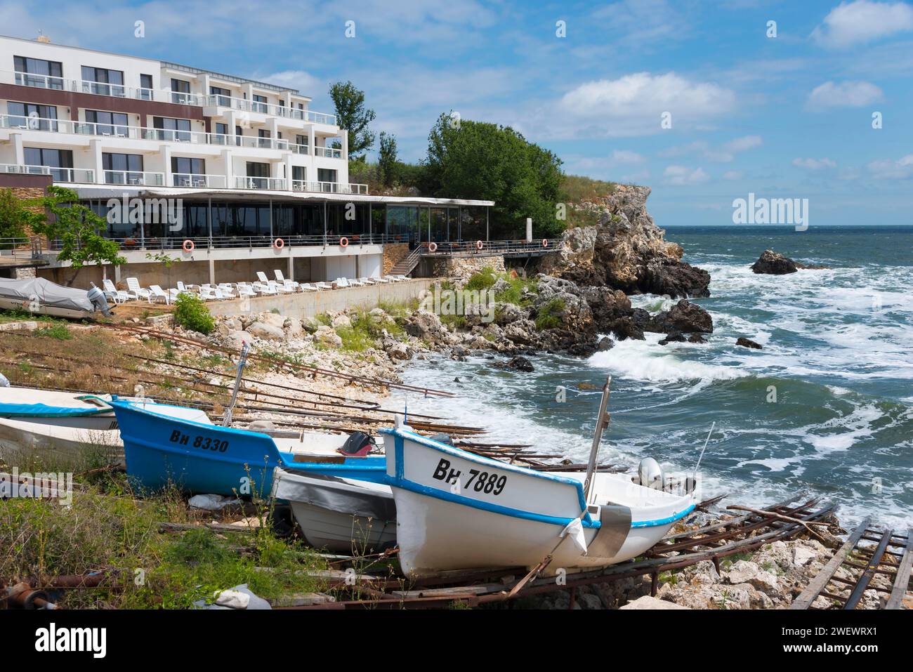 A coastal hotel overlooking the moving sea, surrounded by boats and ...