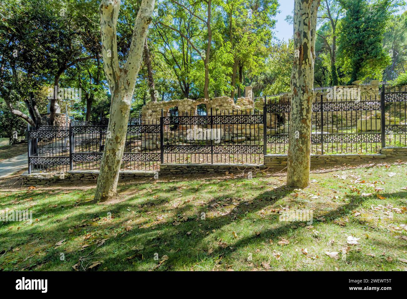 Ruins of ancient roman era behind black iron fence in public park in ...