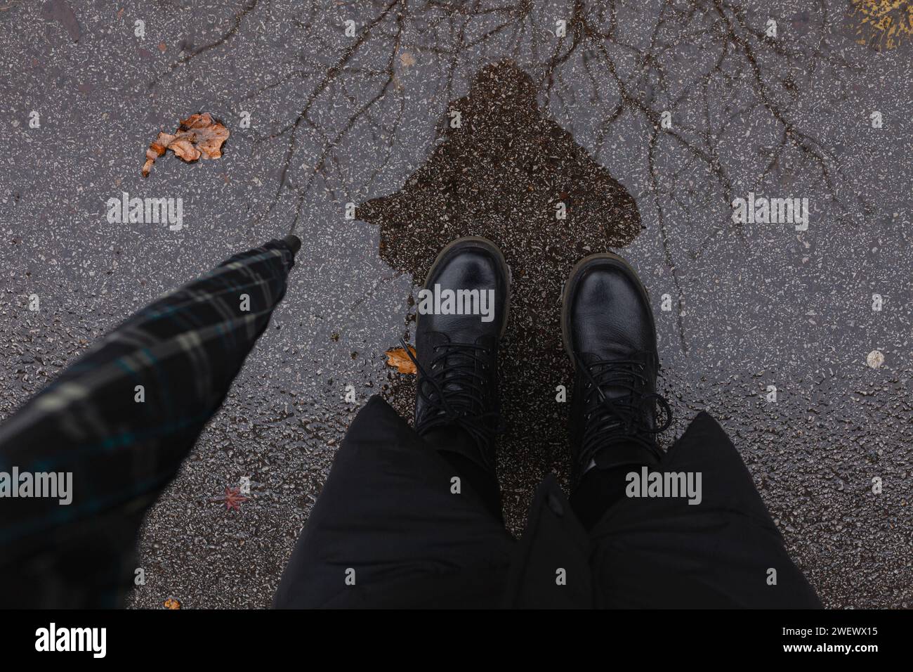 Top view of woman's feet in black winter boots standing in the rain on ...