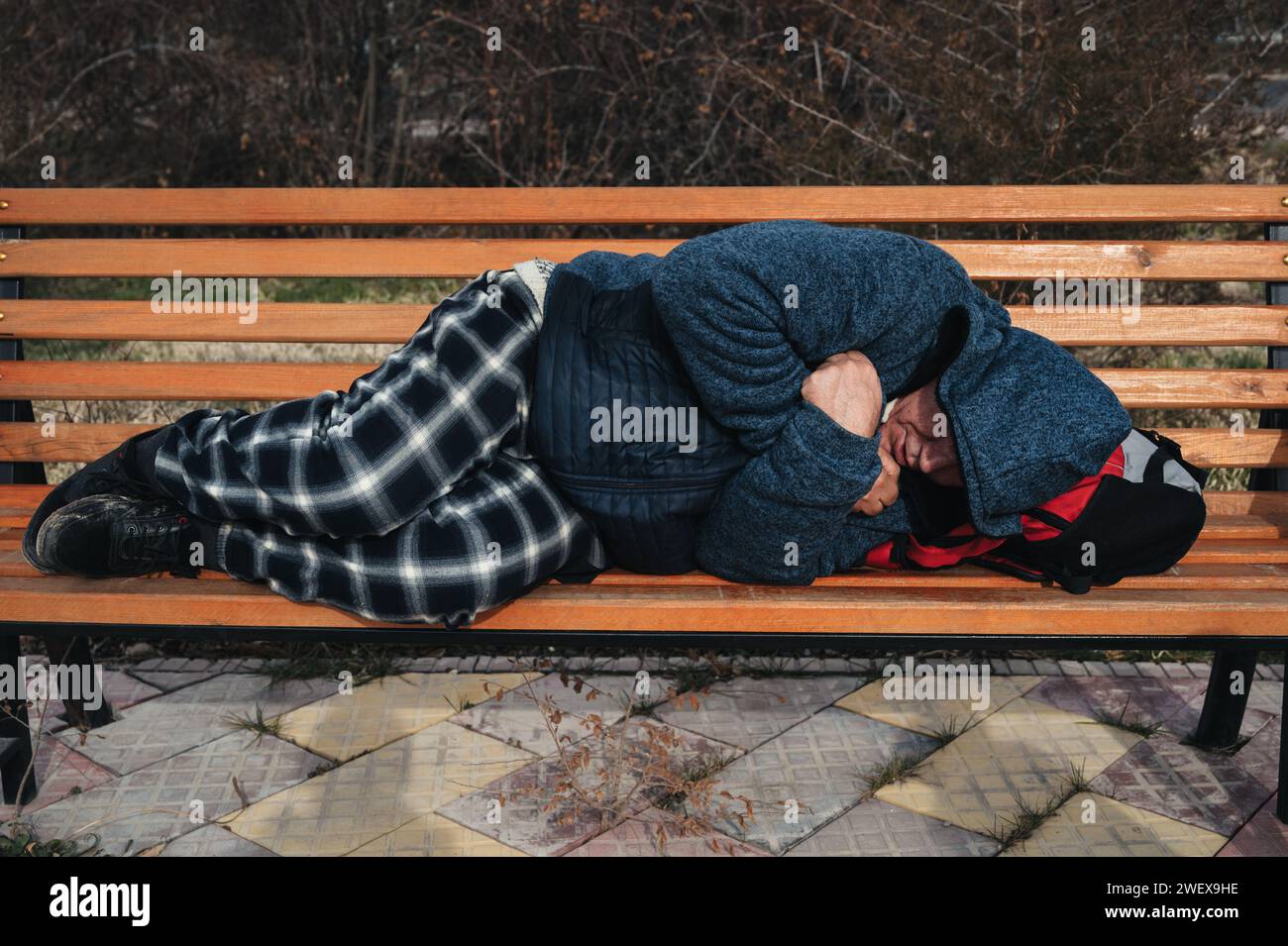 homeless dirty elderly old Caucasian man lies sleeping on a park bench ...