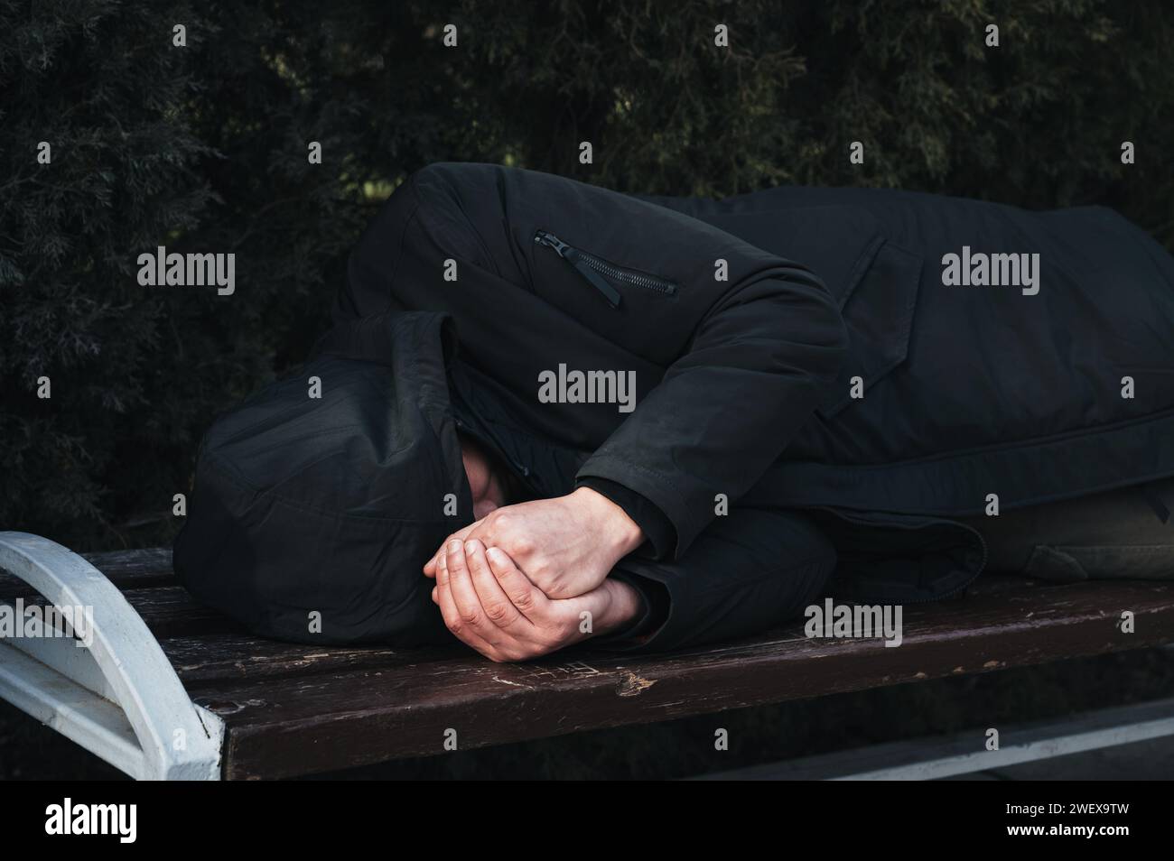 lonely man homeless and upset lies sleeping on a park bench Stock Photo ...