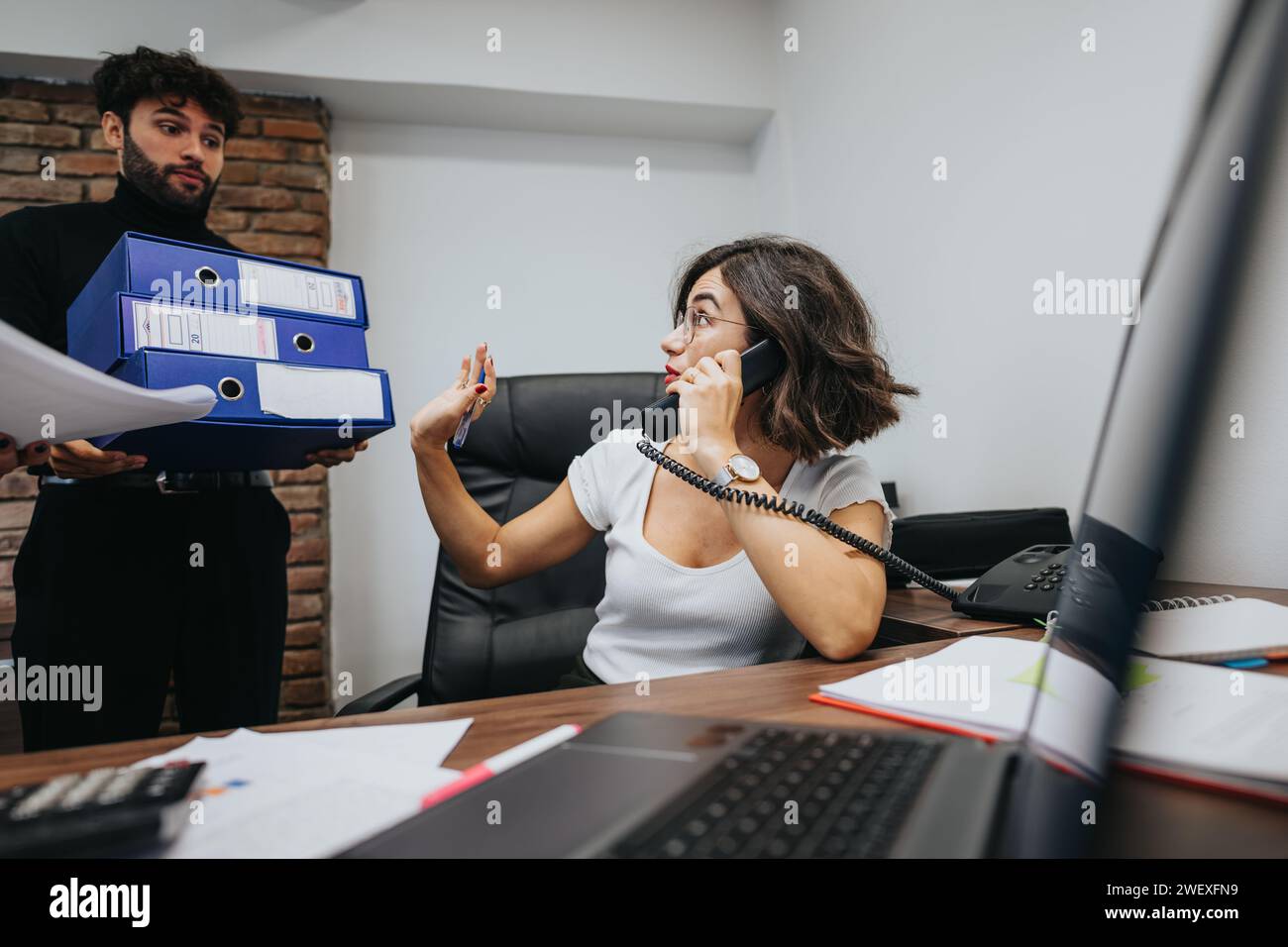 Busy office scenario: Woman multitasking with phone call and man with ...