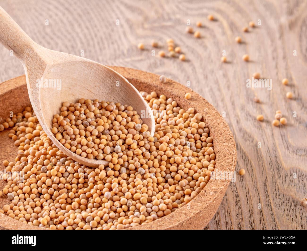 A close-up photo of a wooden spoon filled with mustard seeds, arranged ...