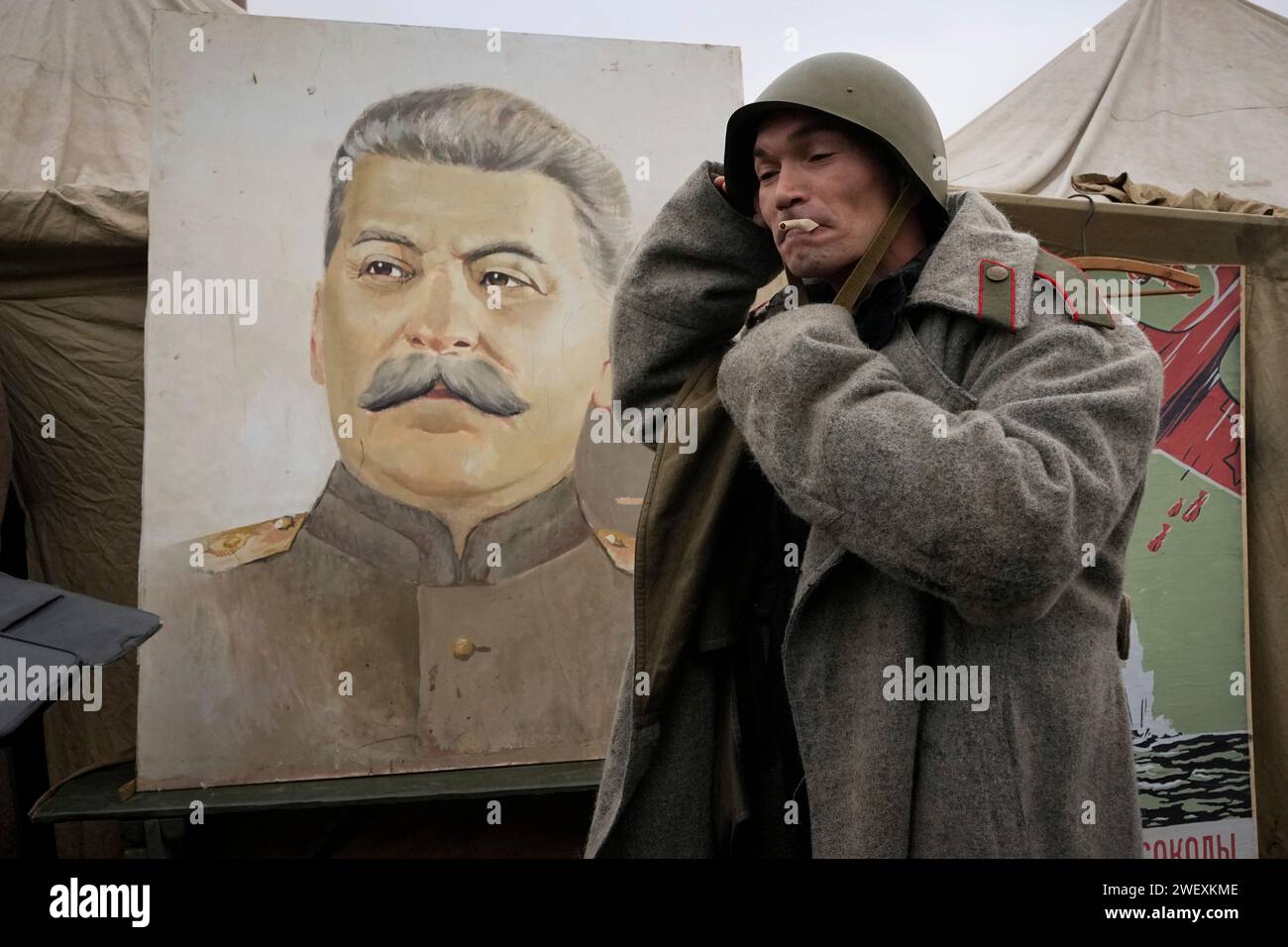 A man wears World War II ages Soviet Army's uniform near a portrait of ...