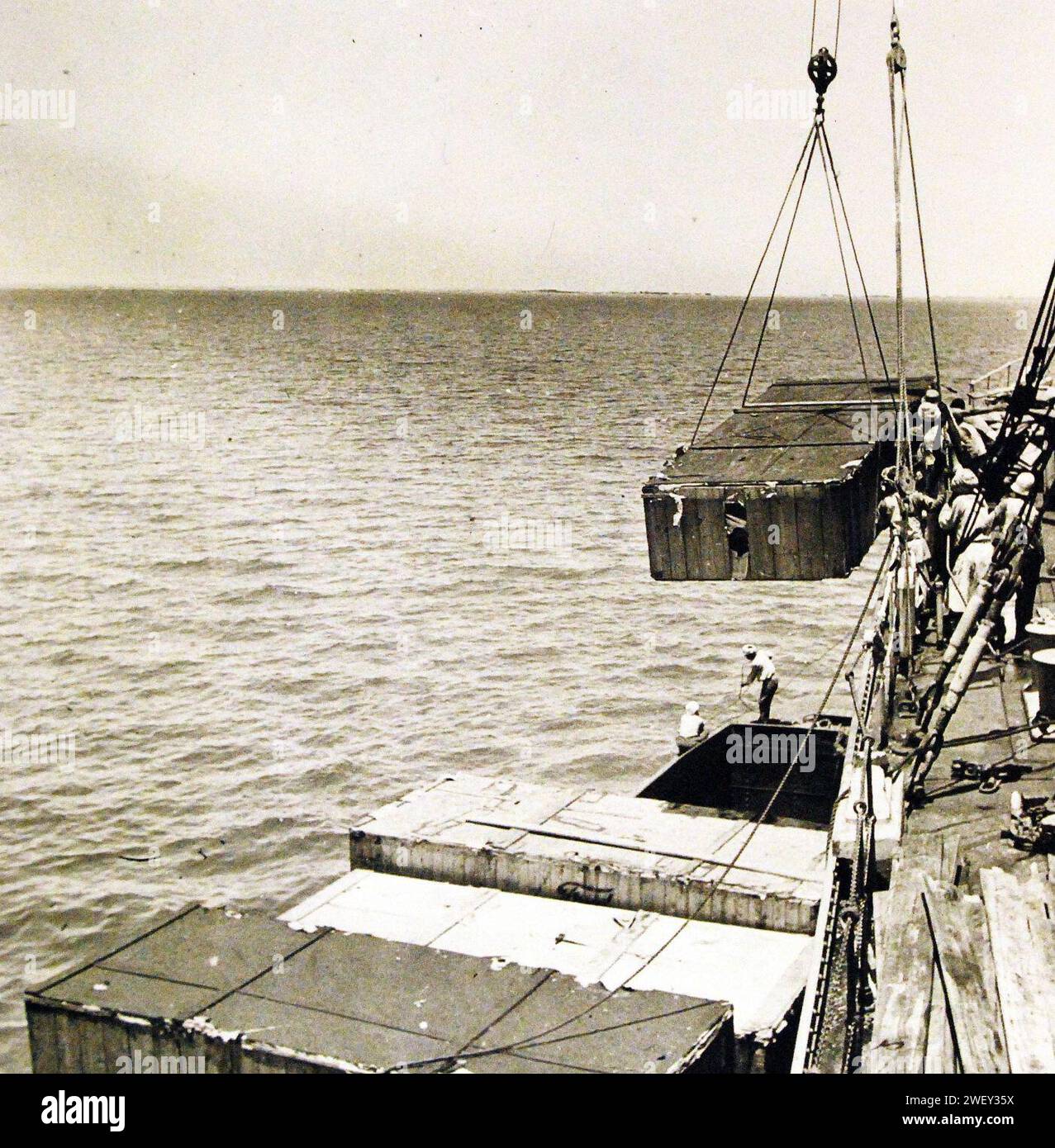 American tanks, automobiles, and trucks being loaded into a barge ...