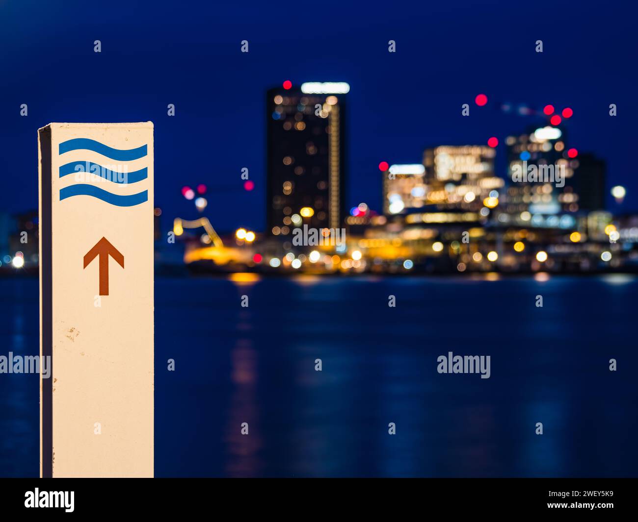 A signpost featuring blue wave symbols and an upward arrow stands in ...