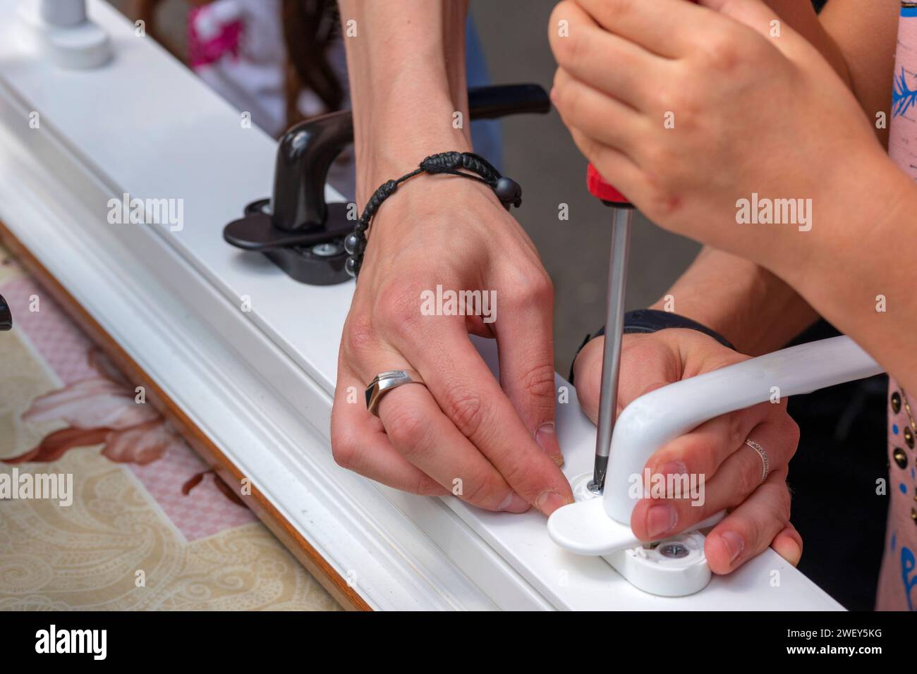 Plastic repair windows. Screwing handles to windows.screwdriver, turn ...