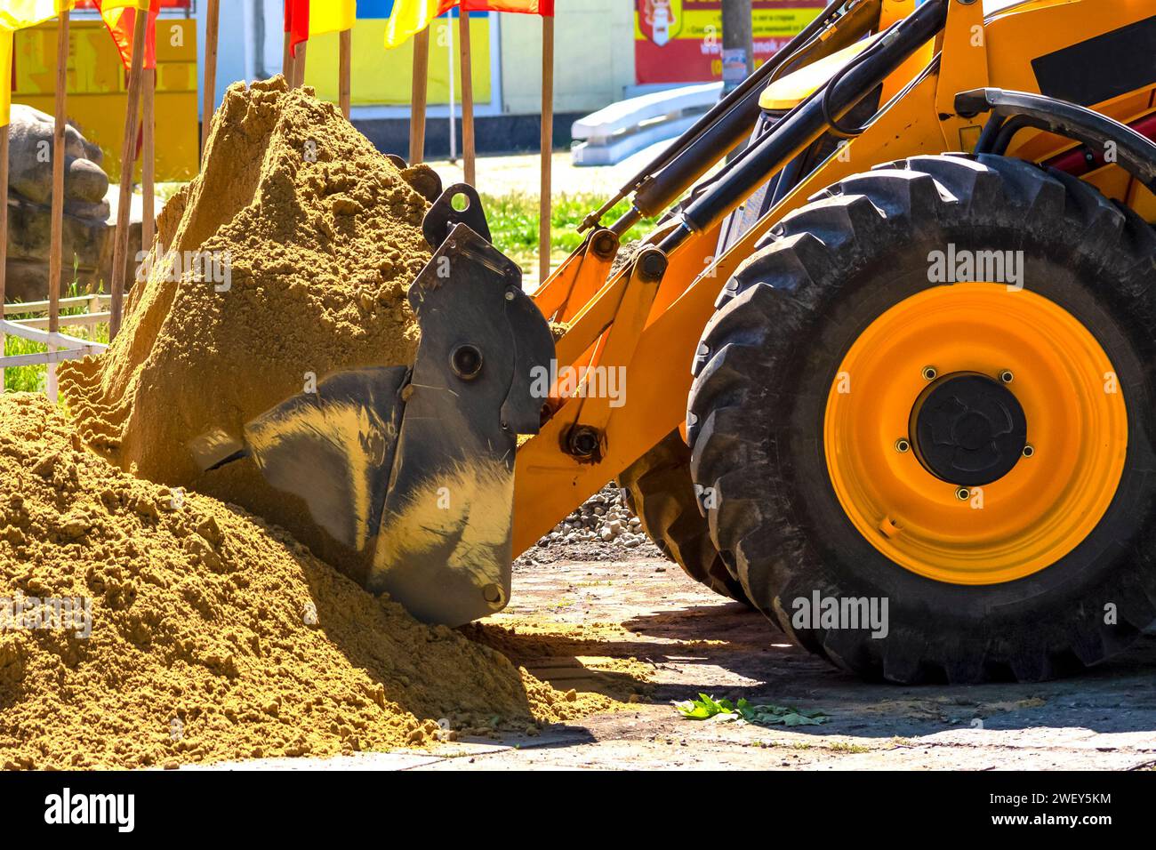 The tractor is rowing sand. Excavator bucket with sand. Road ...