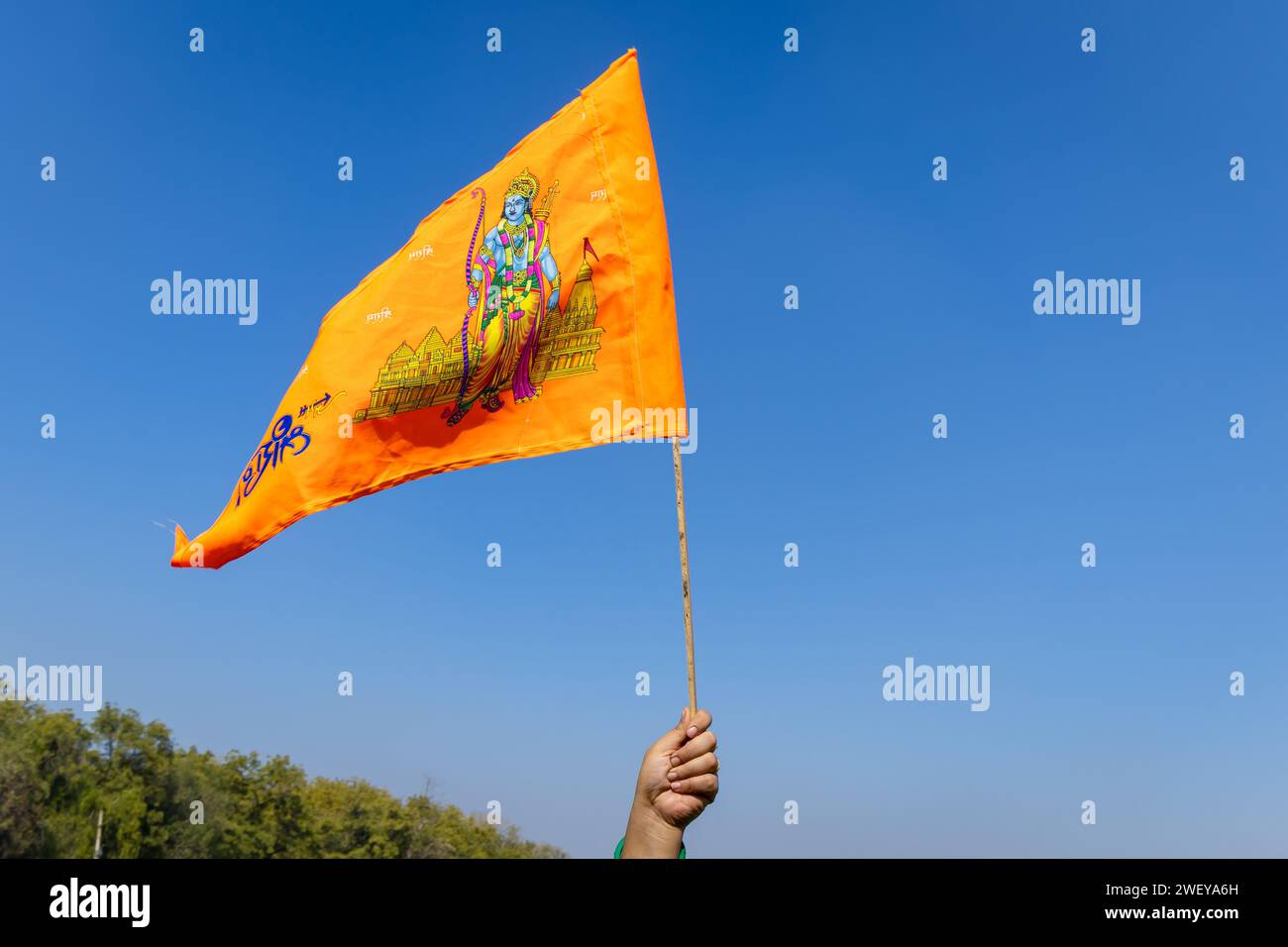 holy saffron flag with lord rama idol holing in hand with bright blue sky background at day ...