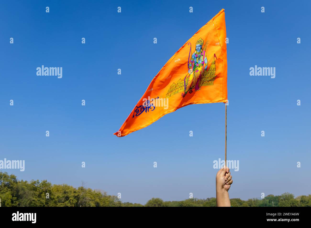 holy saffron flag with lord rama idol holing in hand with bright blue sky background at day ...