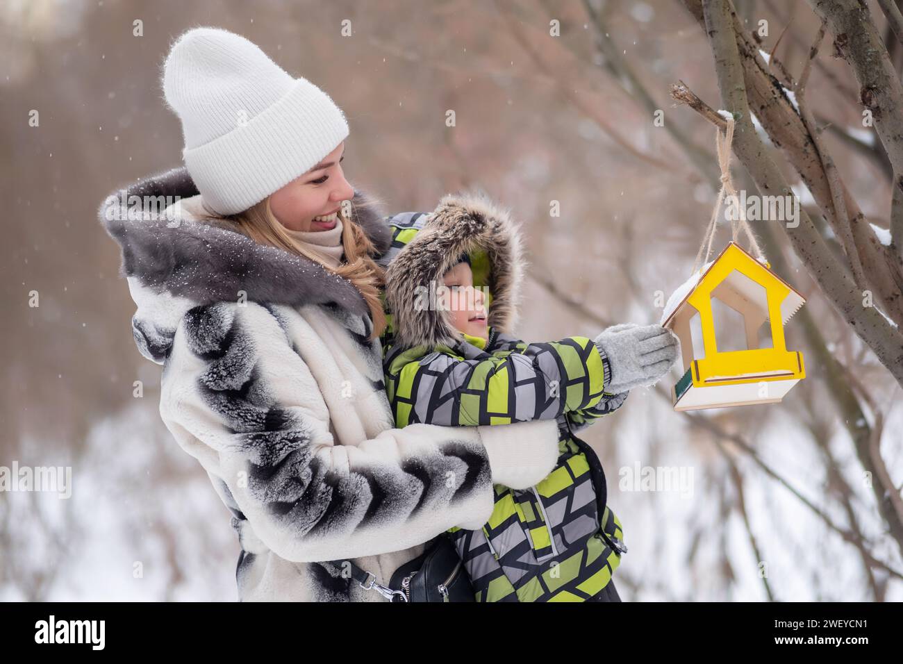 mother and son in a winter park feed birds using a feeder Stock Photo ...
